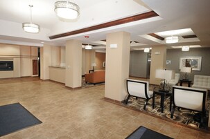 Um saguão de hotel com balcão de recepção, área de estar e uma kitchenette.