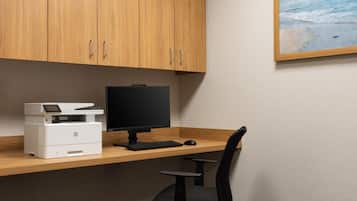 Um espaço de escritório moderno com armários de madeira, um computador de mesa, uma impressora HP e uma cadeira de escritório preta.