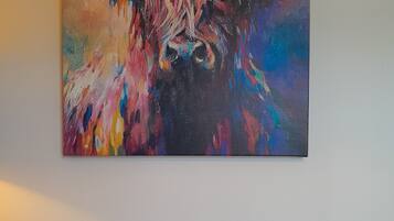 Pintura de cabeça de touro com um fundo colorido, uma chaleira, uma cafeteira e uma bandeja com chávenas e um carregador sobre uma mesa.