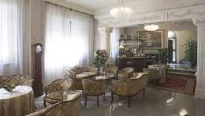 Uma sala de jantar formal com um candelabro, um relógio e um espaço de bar com um quadro.