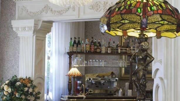 Uma área de bar com um candelabro, uma luminária de vitral e um balcão.
