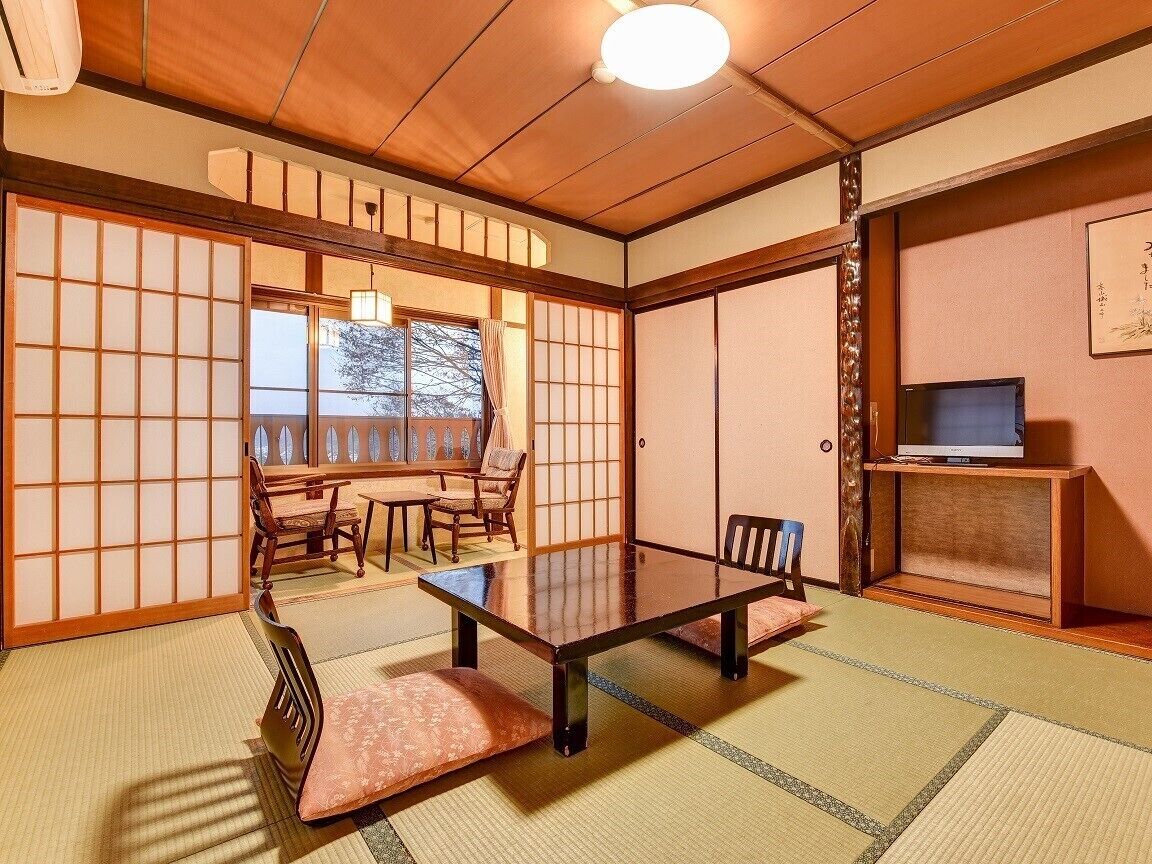 Um quarto japonês tradicional com tatames, uma mesa baixa e portas deslizantes.