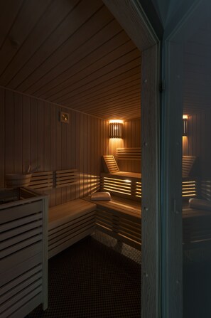 Sala de sauna com bancos de madeira e piso ladrilhado.