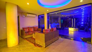 Um interior moderno com um conjunto de sofá de vime, uma divisória de vidro e um teto com iluminação circular.