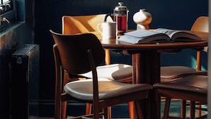 Uma área de refeições aconchegante com cadeiras de madeira, uma mesa e uma obra de arte emoldurada na parede.