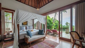 Um quarto com cama de dossel, um sofá, uma poltrona e vista para o jardim.