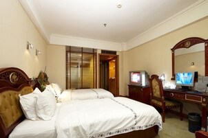 Quarto de hotel com duas camas, uma televisão, uma escrivaninha com computador e um espelho.