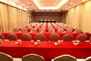 Sala de conferências com mesas e cadeiras dispostas em fileiras, equipada com placas de identificação e garrafas de água.