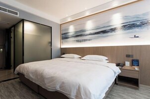 Quarto de hotel moderno com uma cama grande, uma mesa de cabeceira e uma obra de arte na parede.