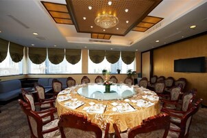 Sala de conferências com uma mesa redonda, cadeiras e um lustre.