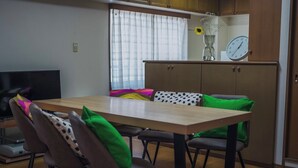 Uma sala de jantar com uma mesa de madeira, cadeiras e um relógio na parede.