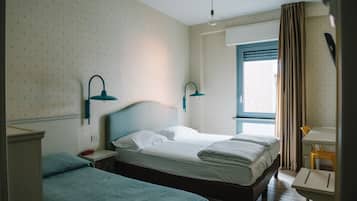 Quarto de hotel com duas camas, uma mesa e uma cadeira.