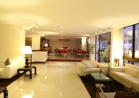 Uma sala de estar ampla com um sofá, uma mesa de centro e um espaço de refeições com cadeiras vermelhas.