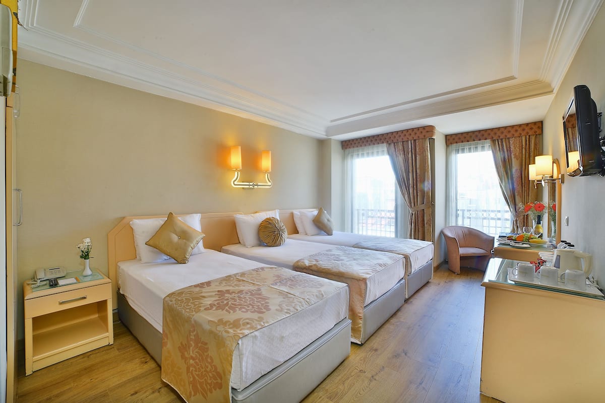Quarto de hotel com duas camas, uma escrivaninha e uma cadeira.