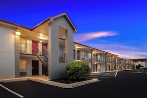Um motel com vários andares, uma escadaria central e fachada bem iluminada.