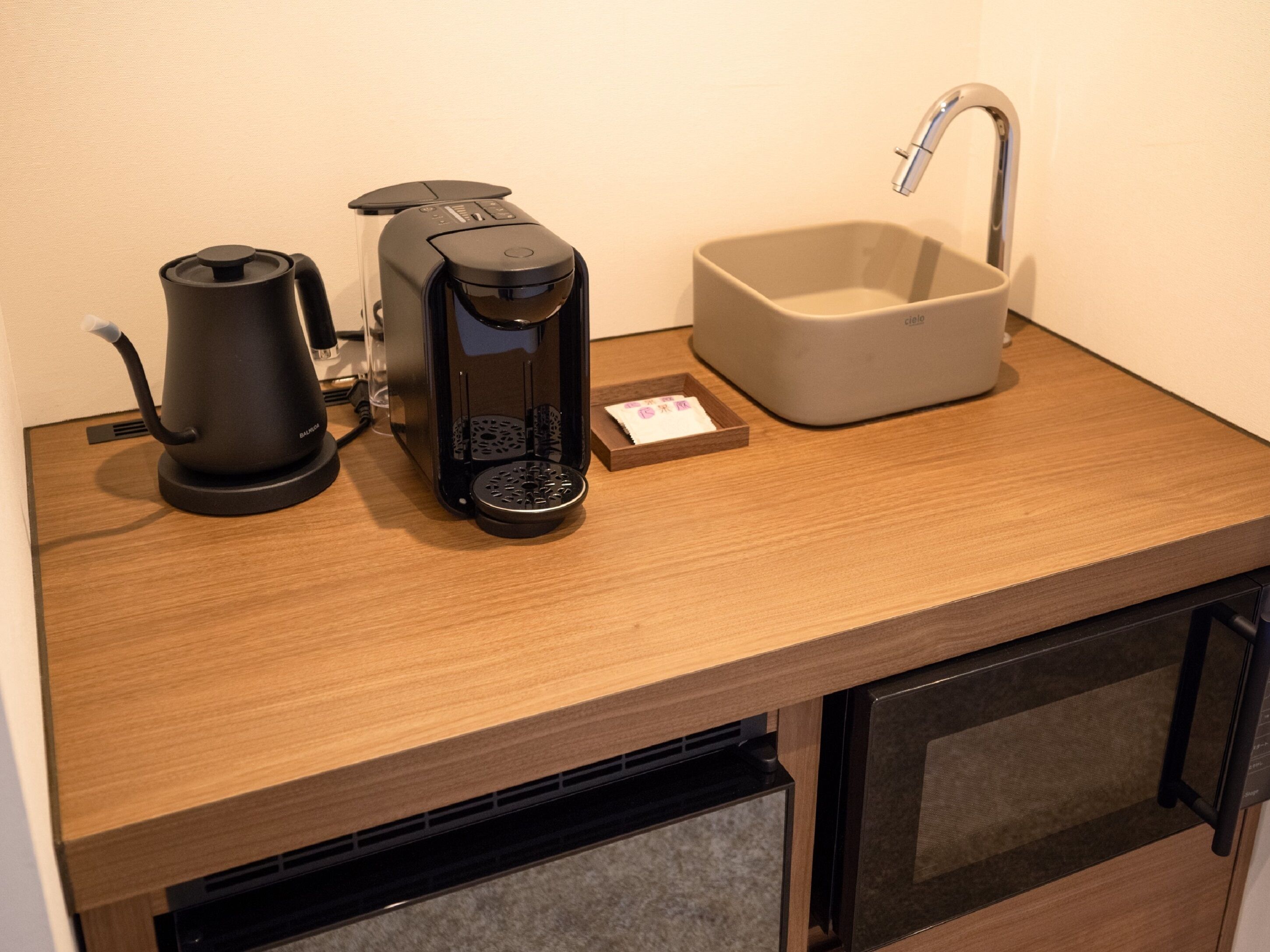 Uma cozinha compacta com cafeteira, chaleira e pia.