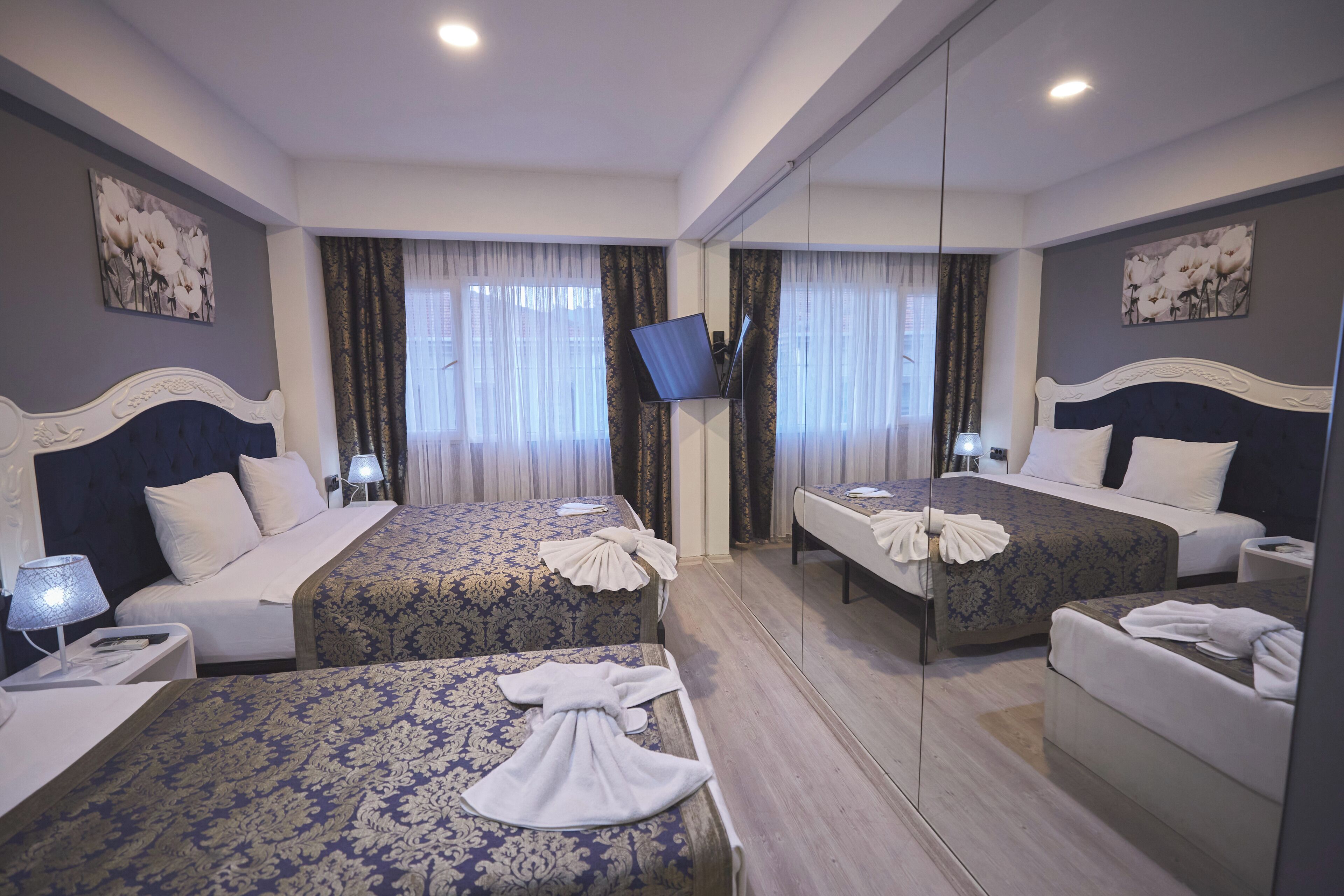 Quarto de hotel com duas camas, televisão e um espelho grande.