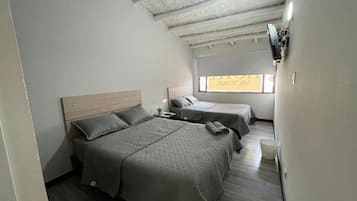 Quarto com duas camas, cabeceira de madeira, janela com vista e teto com vigas aparentes.