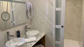 Casa de banho com duas pias, um espelho, um porta-toalhas e zona de duche.