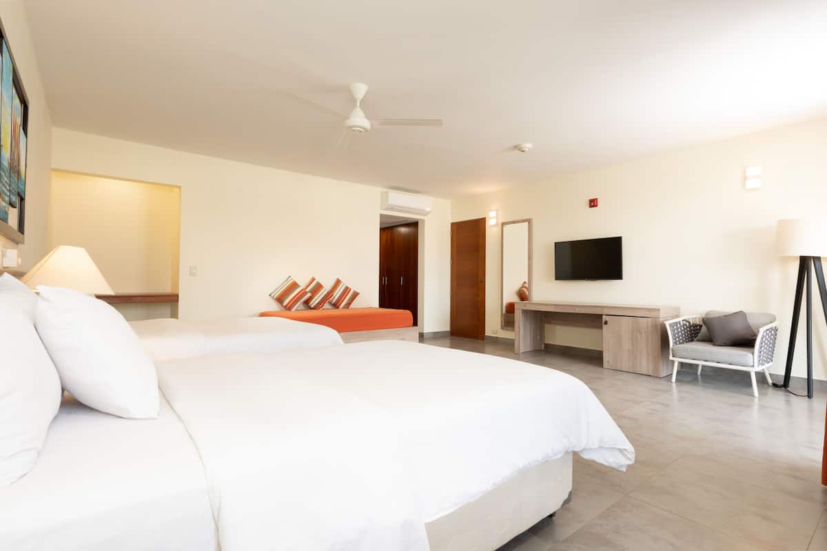 Quarto de hotel com duas camas, uma escrivaninha, uma televisão e uma cadeira.