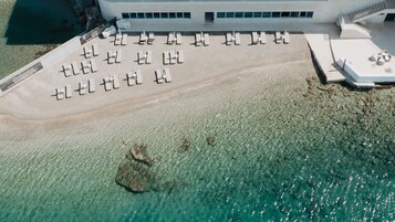 Praia particular, espreguiçadeiras, guarda-sóis, toalhas de praia 
