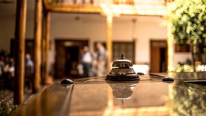 Um saguão de hotel com uma mesa de recepção e um reflexo no chão polido.