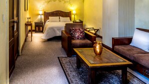 Quarto de hotel com uma cama, duas mesas de cabeceira, uma cadeira, um sofá e uma mesa de centro.