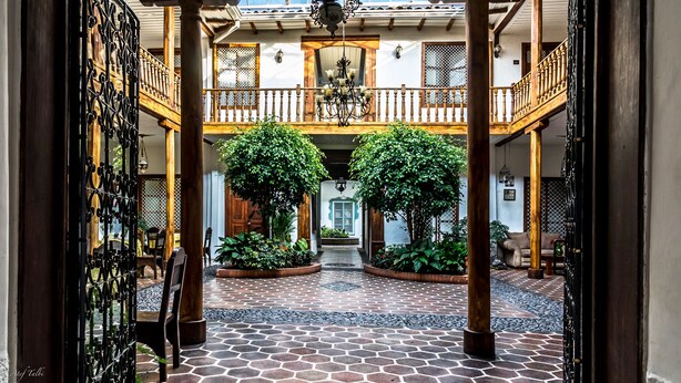Um pátio com varanda de madeira, um candelabro e plantas em vasos.