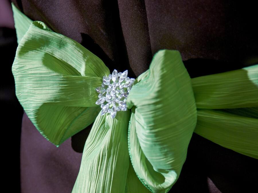 Uma fita verde amarrada em laço com um centro brilhante, provavelmente um detalhe decorativo.