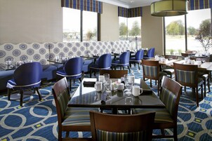 Um restaurante com parede estampada, assentos estofados em azul e tapete padronizado.