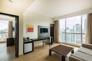 Quarto de hotel moderno com vista para a cidade, televisão de tela plana, escrivaninha, pequena cozinha e sofá.