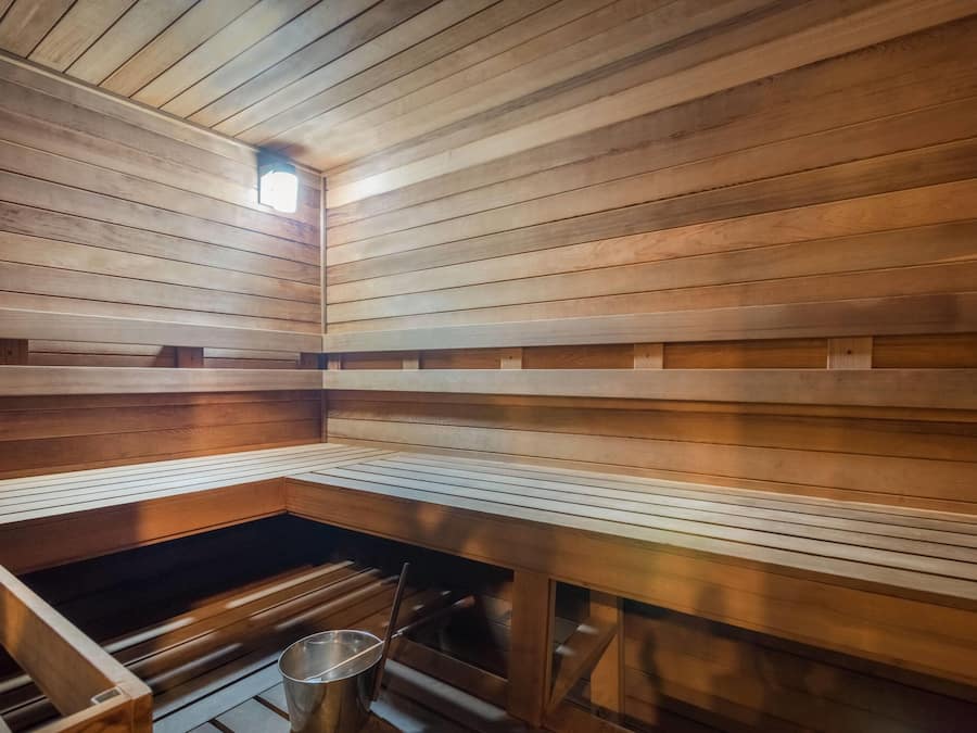 Uma sauna com bancos de madeira e um balde de metal.