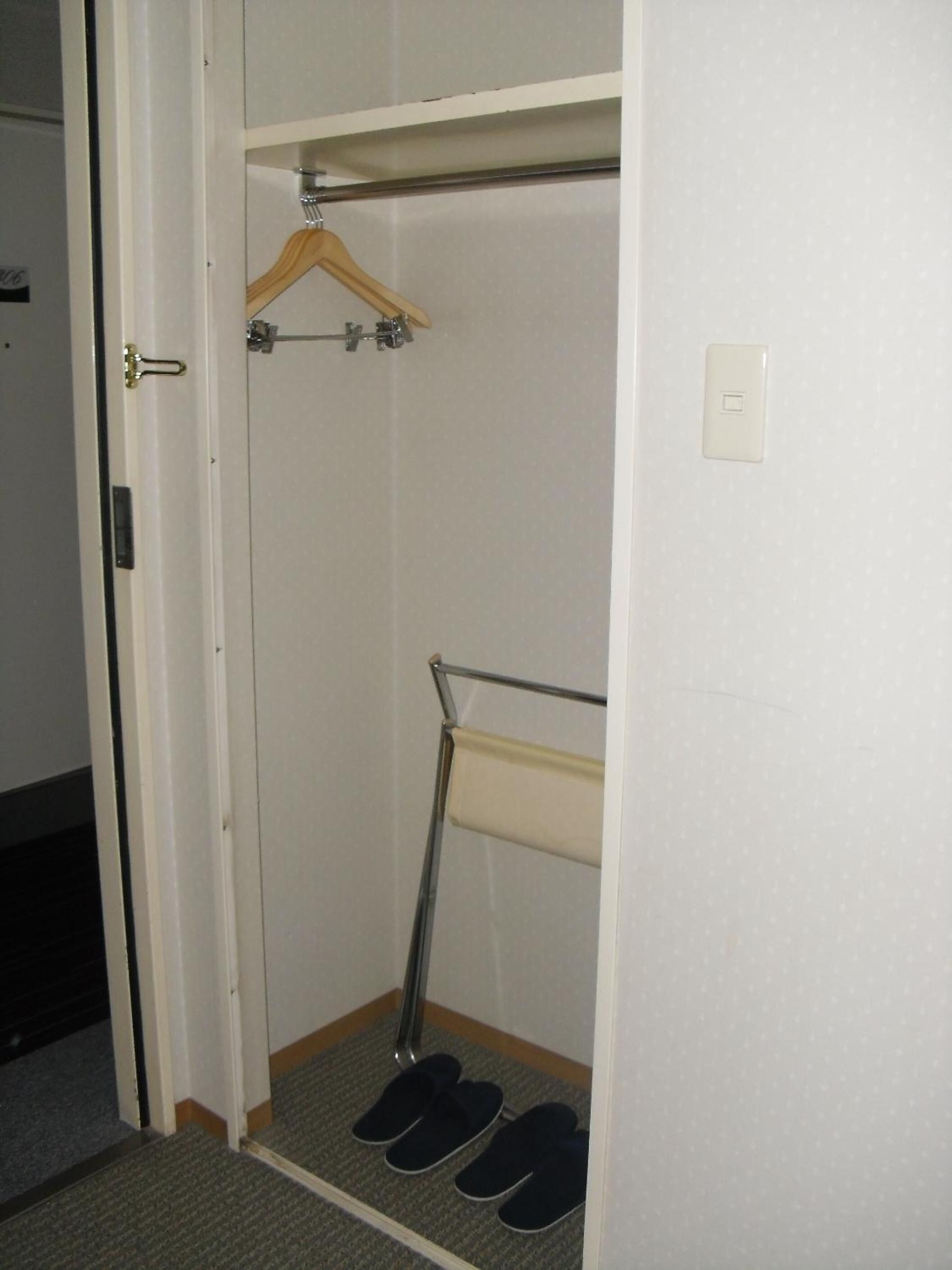Um closet espaçoso com sapateira, cabideiro e porta.