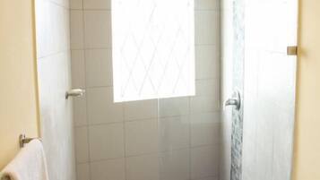 Um pequeno banheiro com azulejos, uma janela, um porta-toalhas e um vaso sanitário.