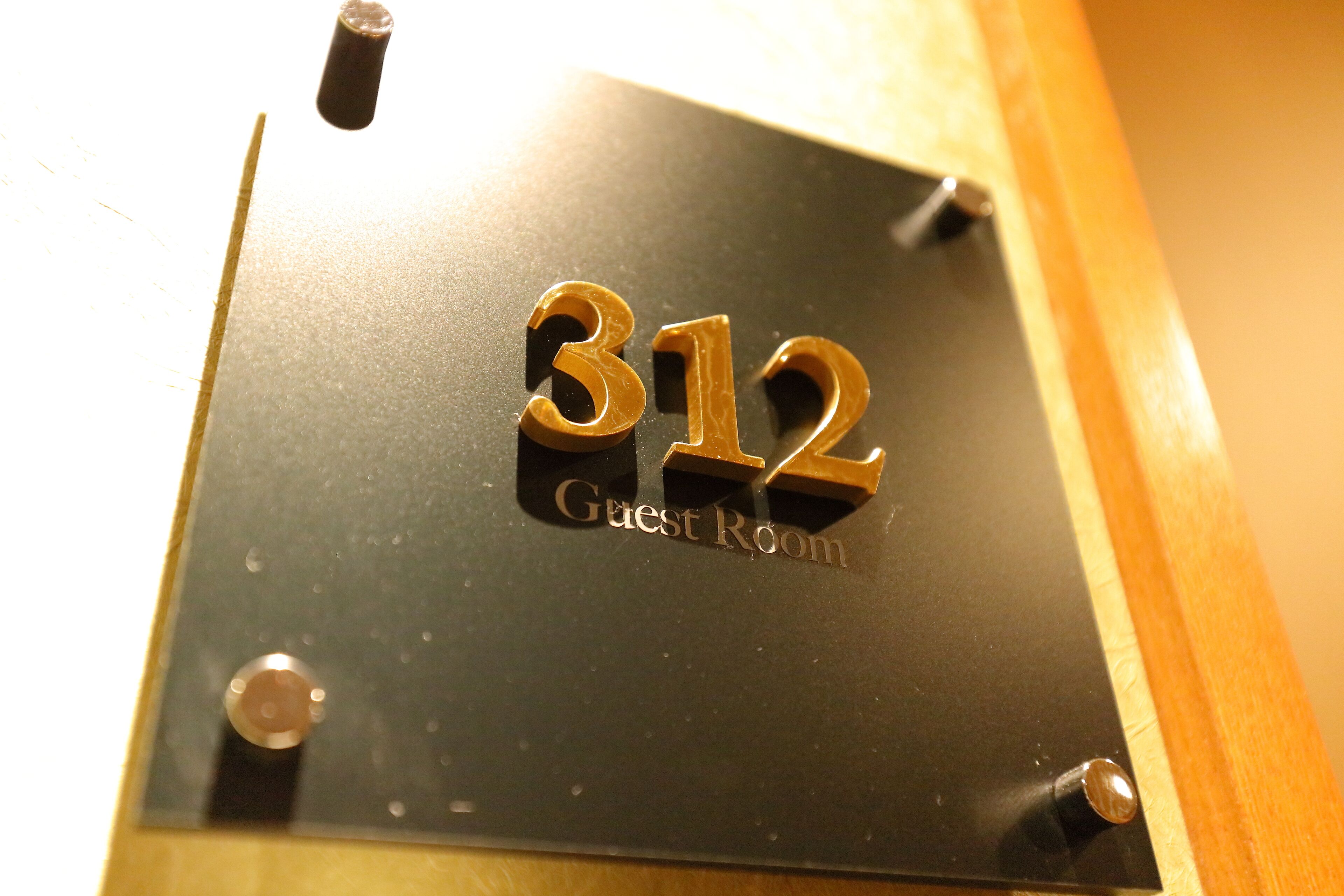 Uma placa preta com o número 312 e a inscrição 'Guest Room', indicando um quarto de hotel.