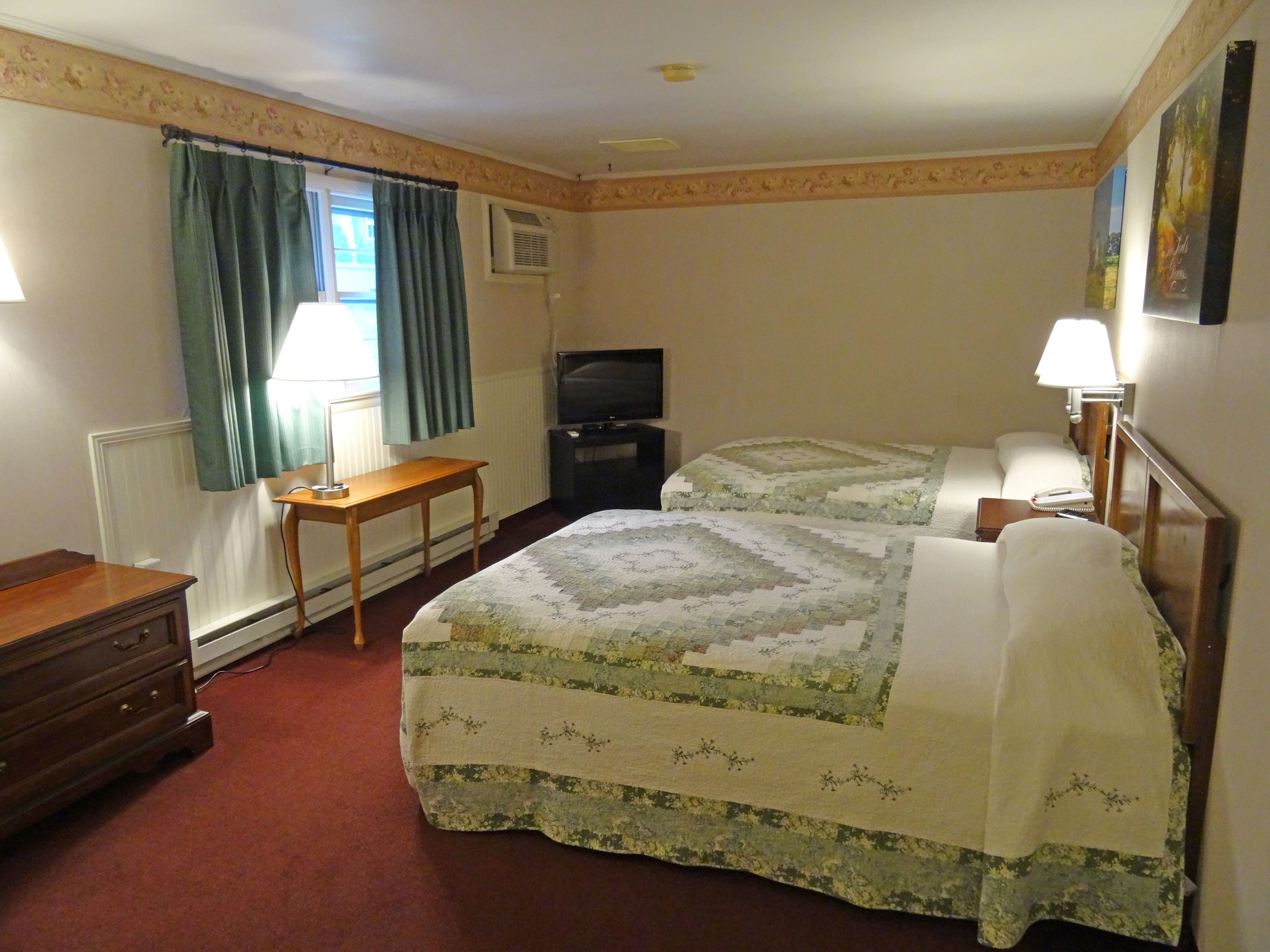Quarto de hotel com duas camas, televisão, secretária e cómoda.