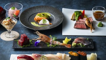 Variedade de pratos de sushi, sashimi e um bife em um prato escuro.