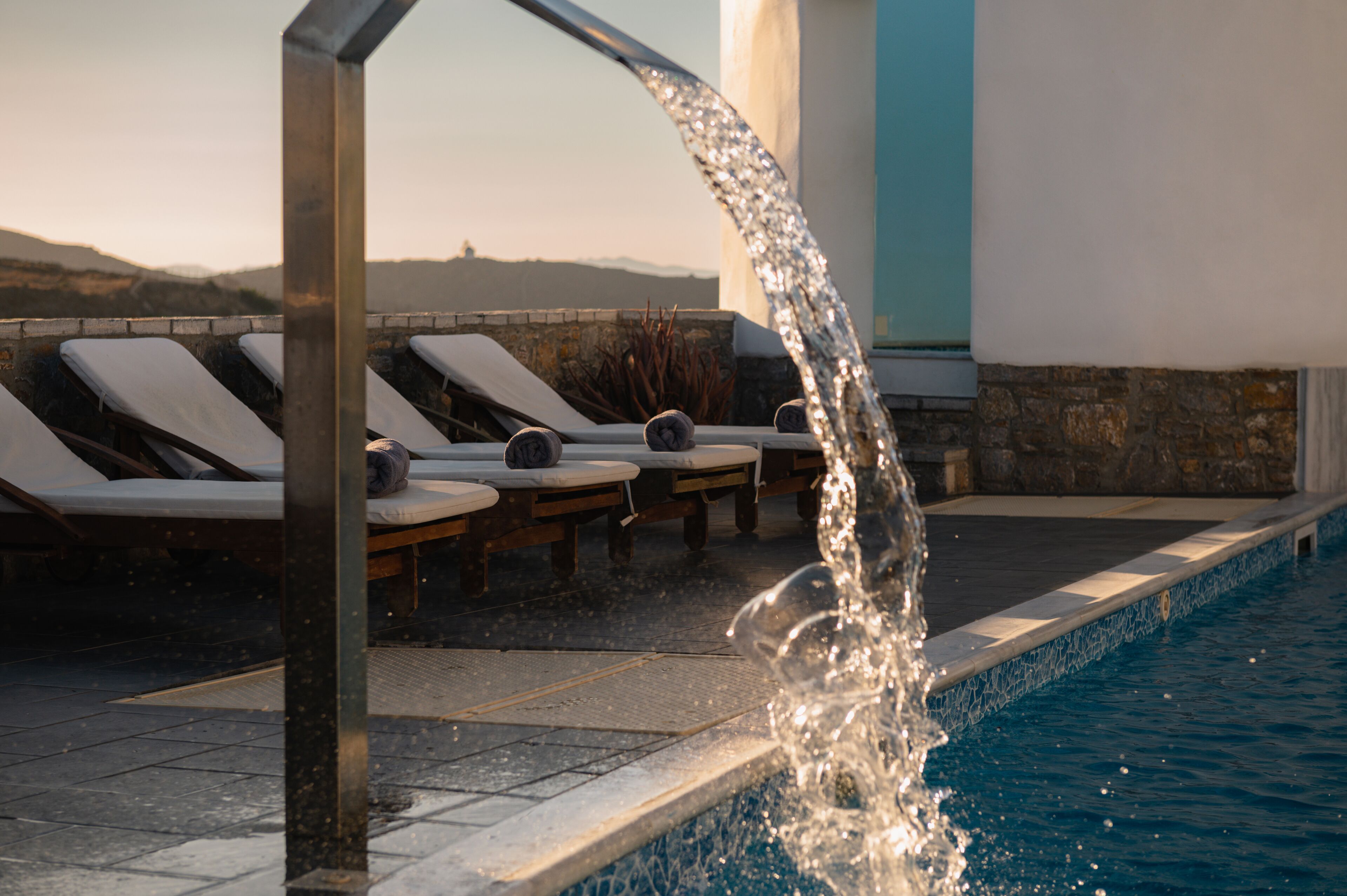 Uma área junto à piscina com espreguiçadeiras e um elemento aquático.