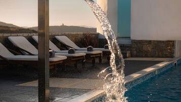 Uma área junto à piscina com espreguiçadeiras e um elemento aquático.