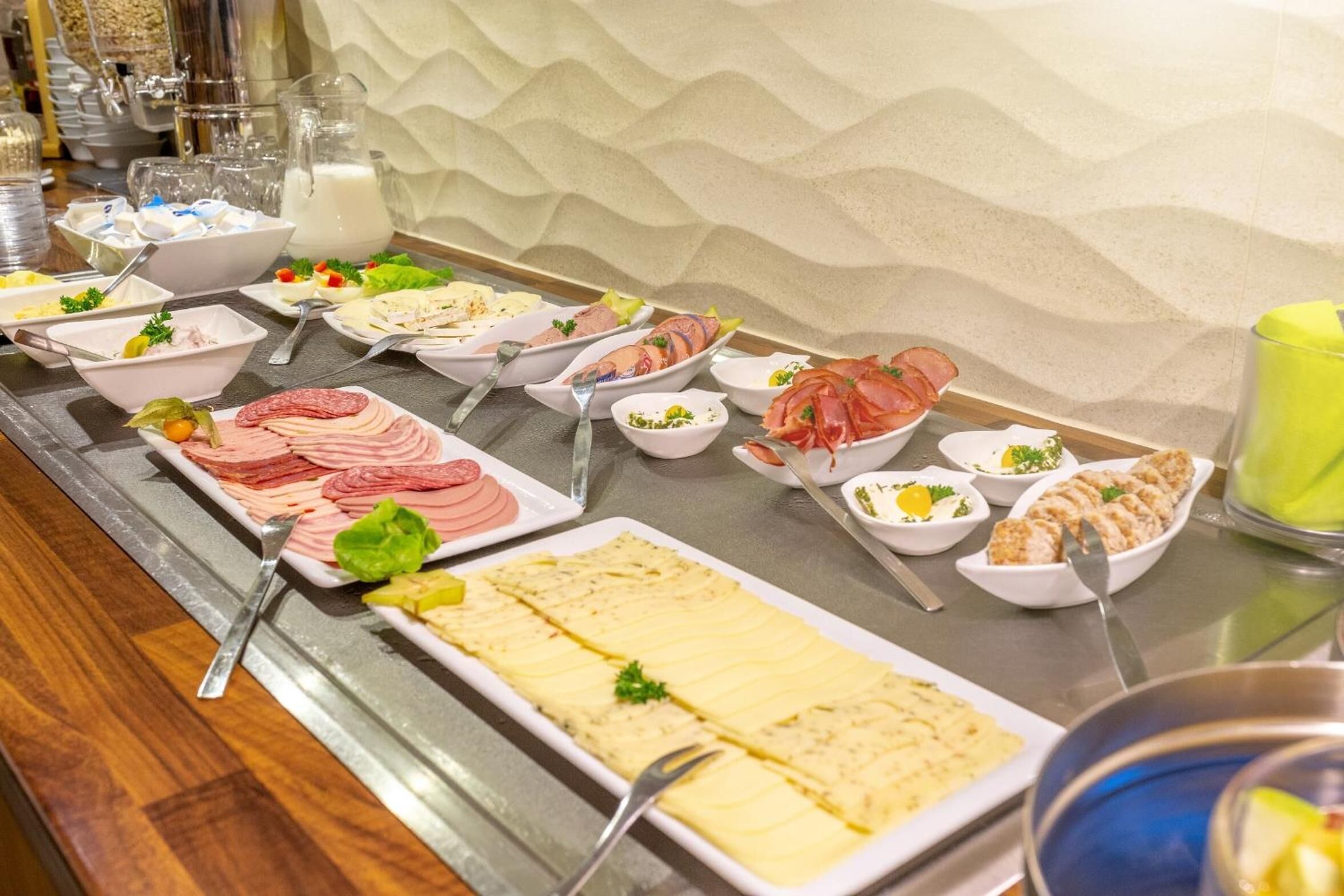 Buffet com diversos alimentos, incluindo carnes, queijos e saladas.