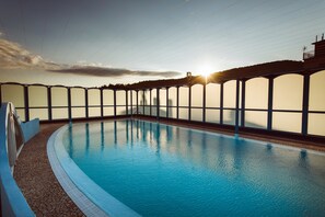 Piscina interna com vista clara para o pôr do sol pelas janelas.