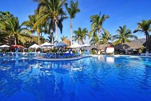 Área de piscina com espreguiçadeiras e guarda-sóis, cercada por palmeiras.