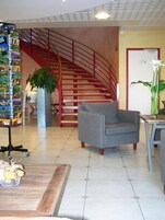 Um saguão com escadas, área de estar e uma exposição de cartões postais.