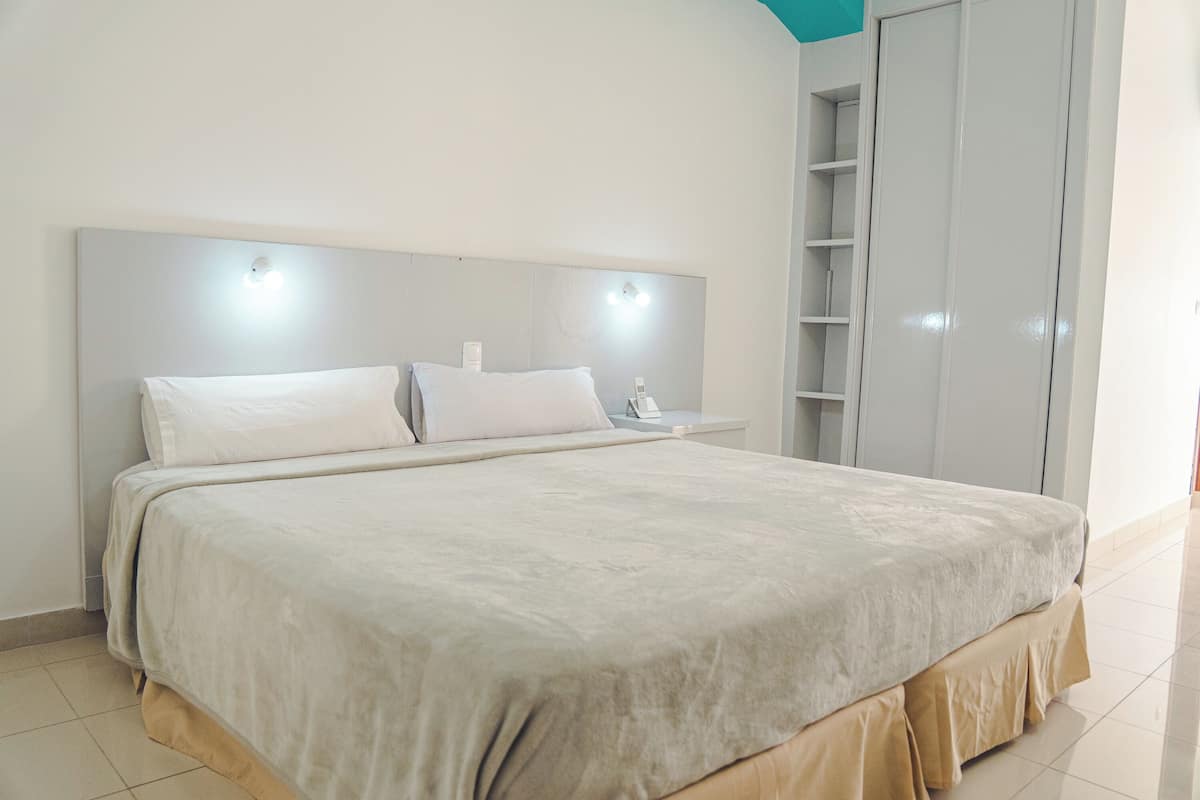 Uma cama grande com cabeceira, mesa de cabeceira e guarda-roupa.