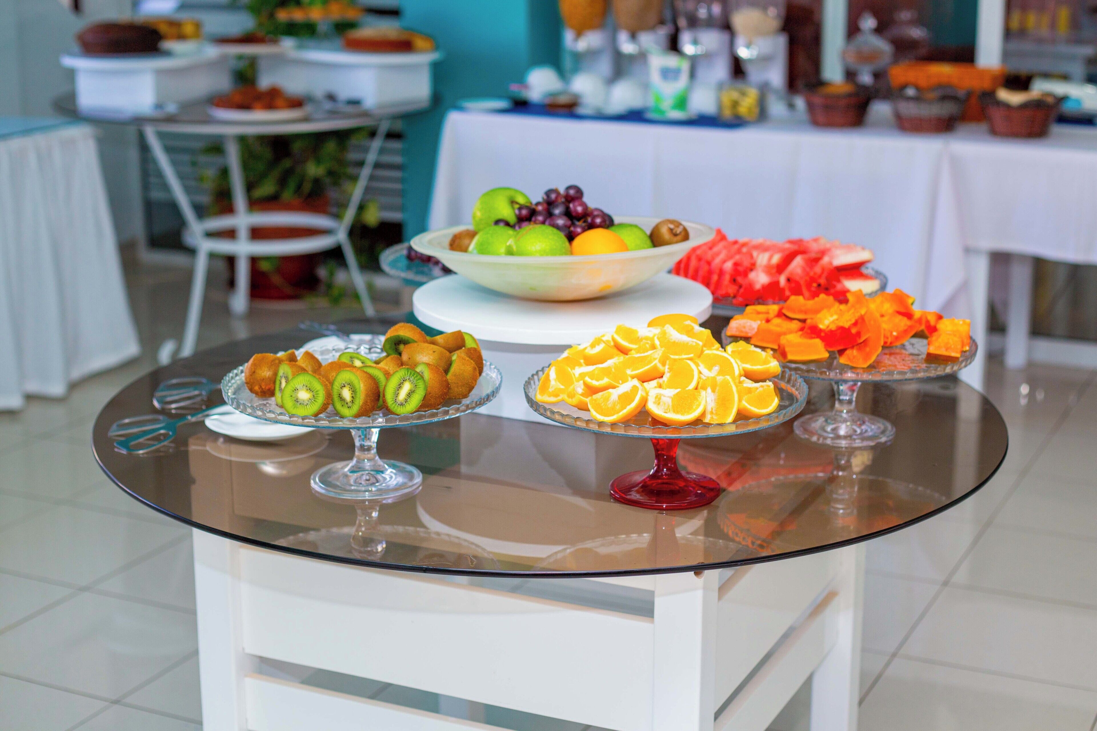 Mesa de buffet com diversas opções de frutas e sobremesas.