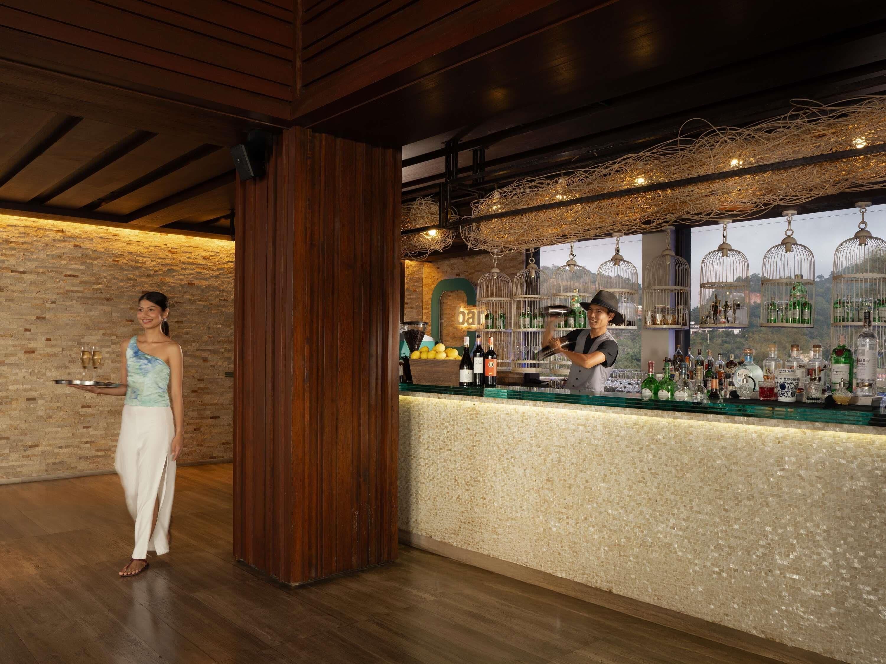 Uma área de bar com um bartender, teto de madeira e parede de tijolos.
