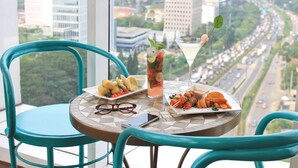 Uma mesa com bebidas, um prato de aperitivos e dois copos, com vista para a cidade.