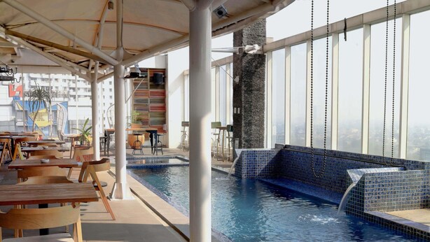 Uma área de piscina com espaço para sentar, mesas e cadeiras.