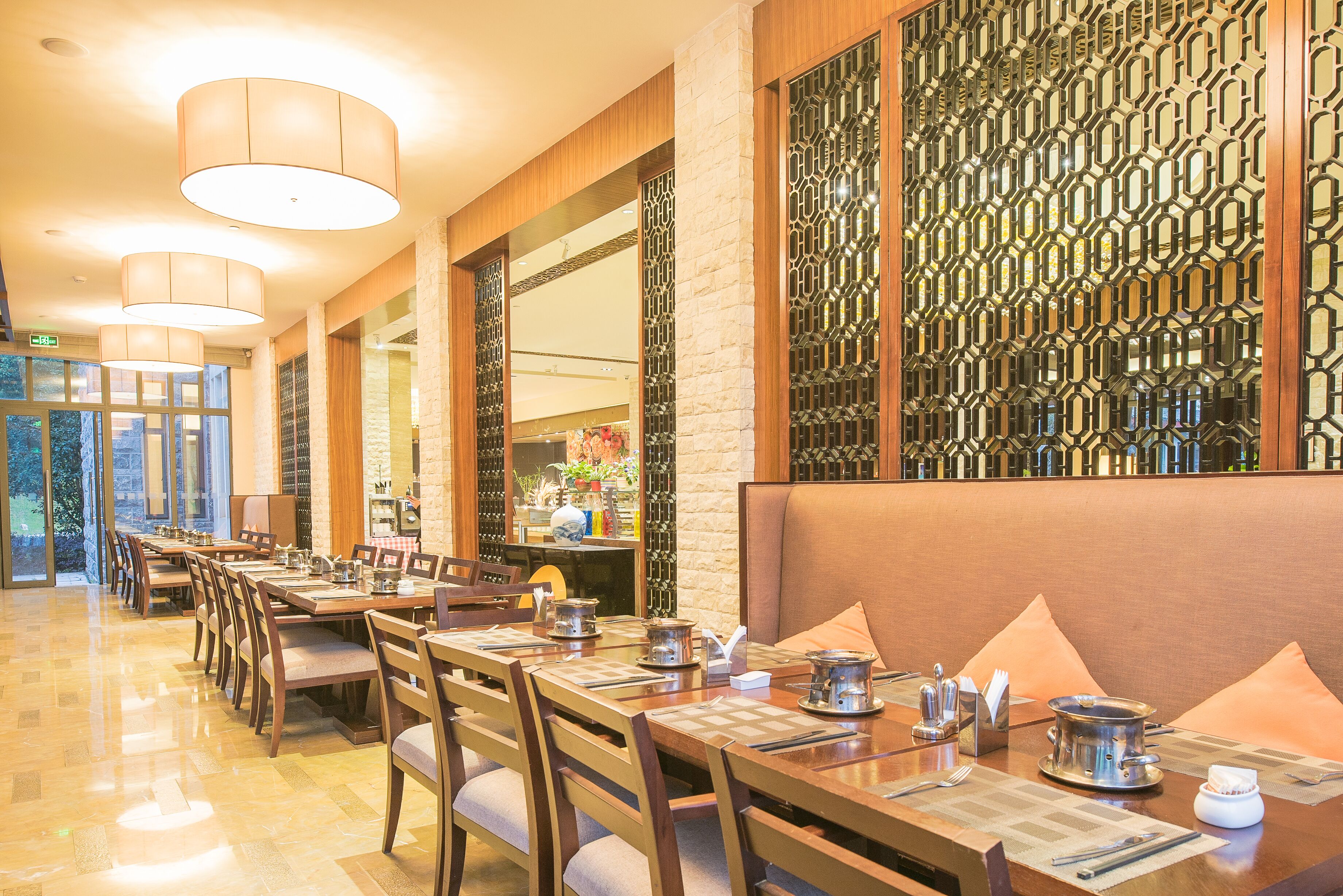 Restaurante com várias mesas, cadeiras e um painel decorativo.