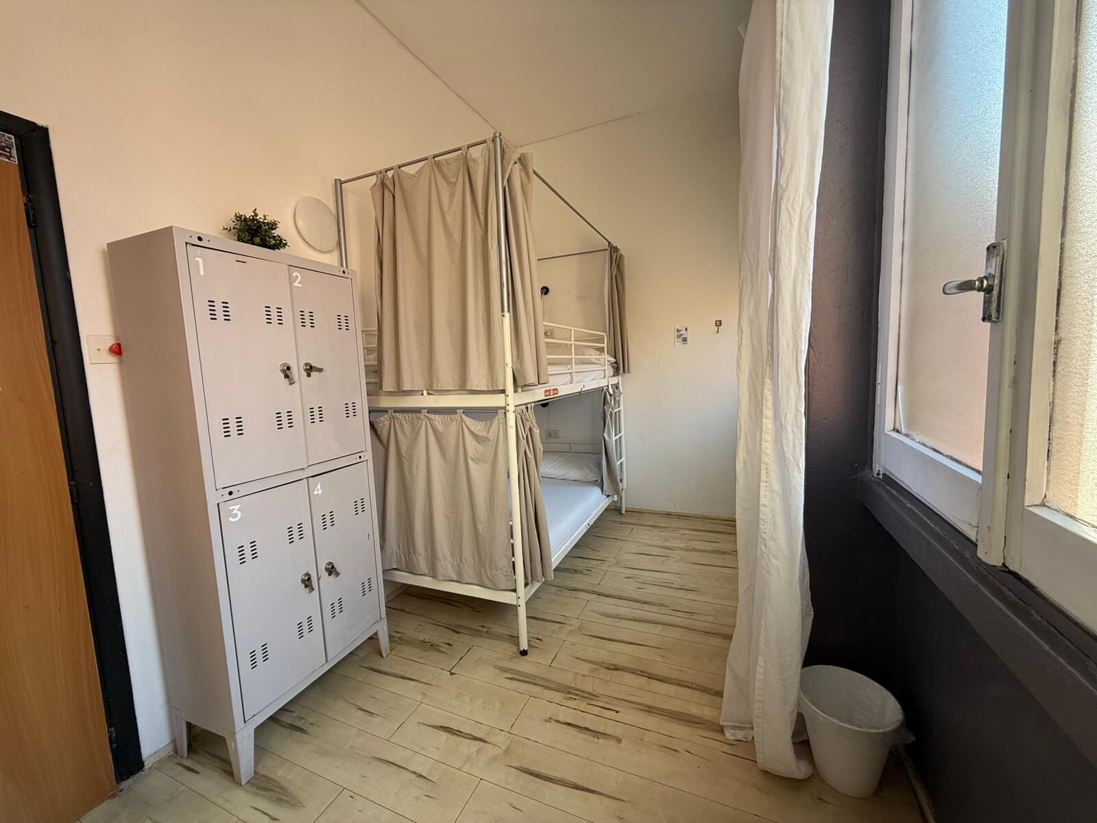 Quarto de estudante com beliches, um guarda-roupa e uma janela.